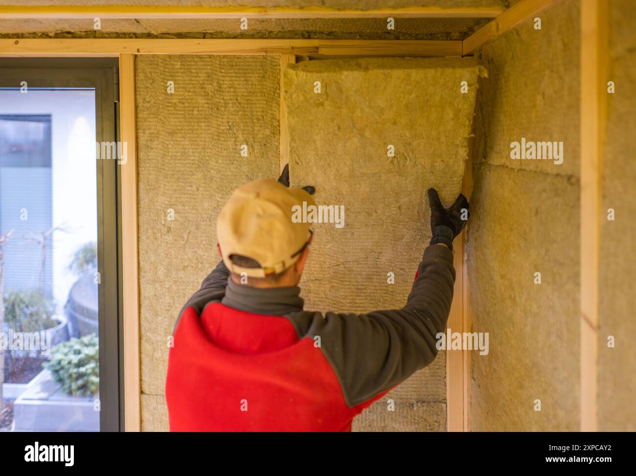 A construction worker wearing gloves and a cap carefully installs ...