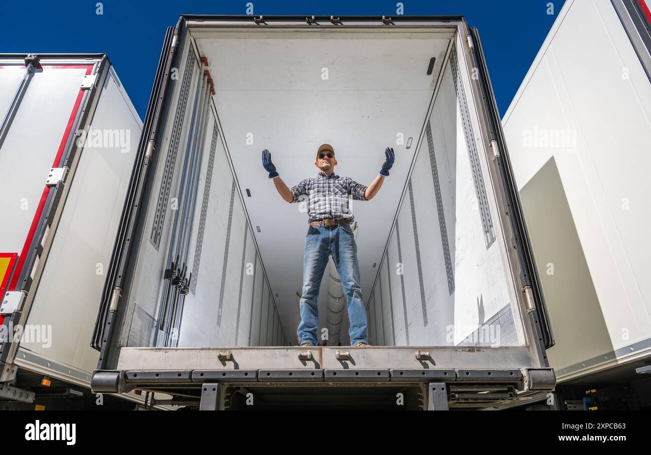 A warehouse worker stands confidently inside an empty semi trailer ...