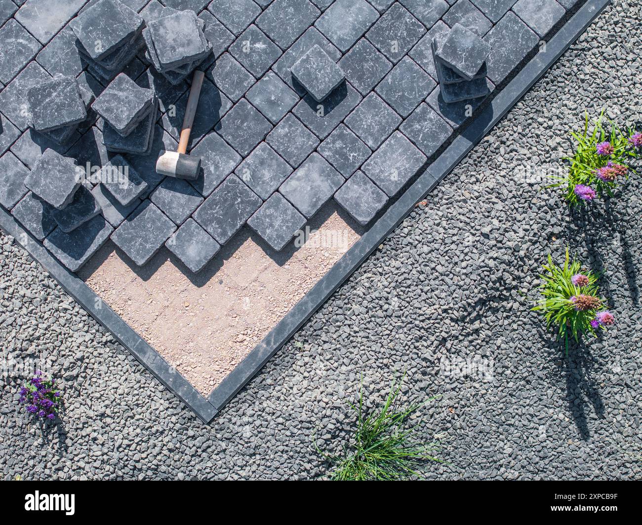 Workers are installing paving stones in a garden pathway, arranging the ...