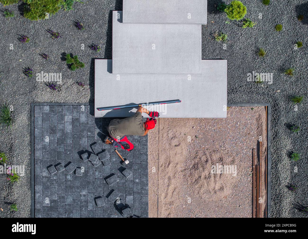 A man works on installing pavers in a well-designed outdoor space ...
