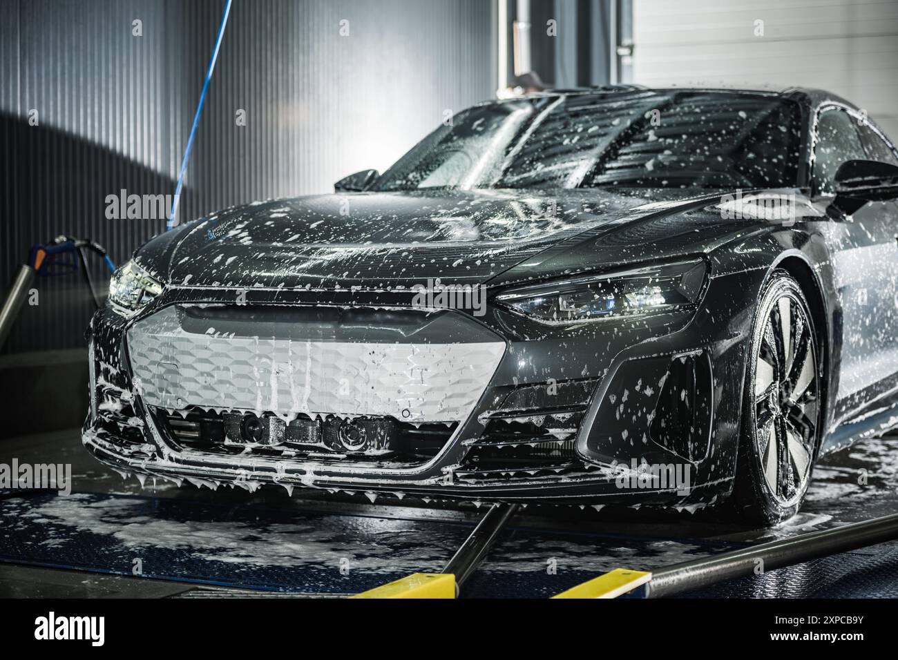 A sleek black car is being washed with soap and water at a contemporary ...