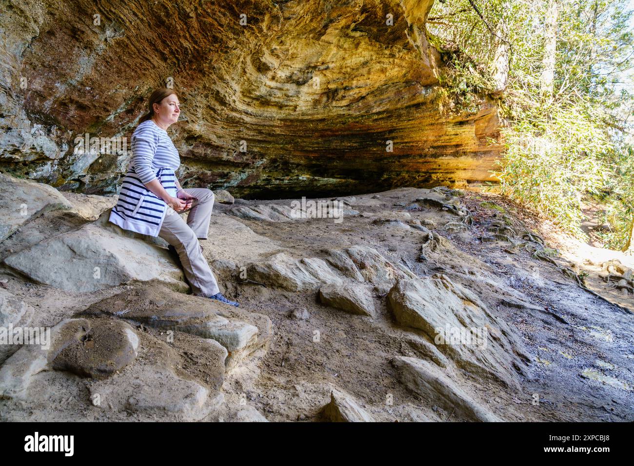 Female hiker taking rest in a small grotto in Red River Gorge in ...