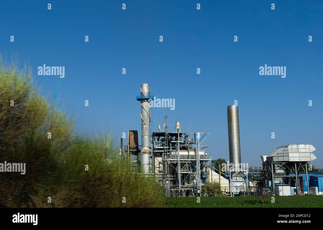 Exterior view of an industrial paper factory surrounded by green plants ...