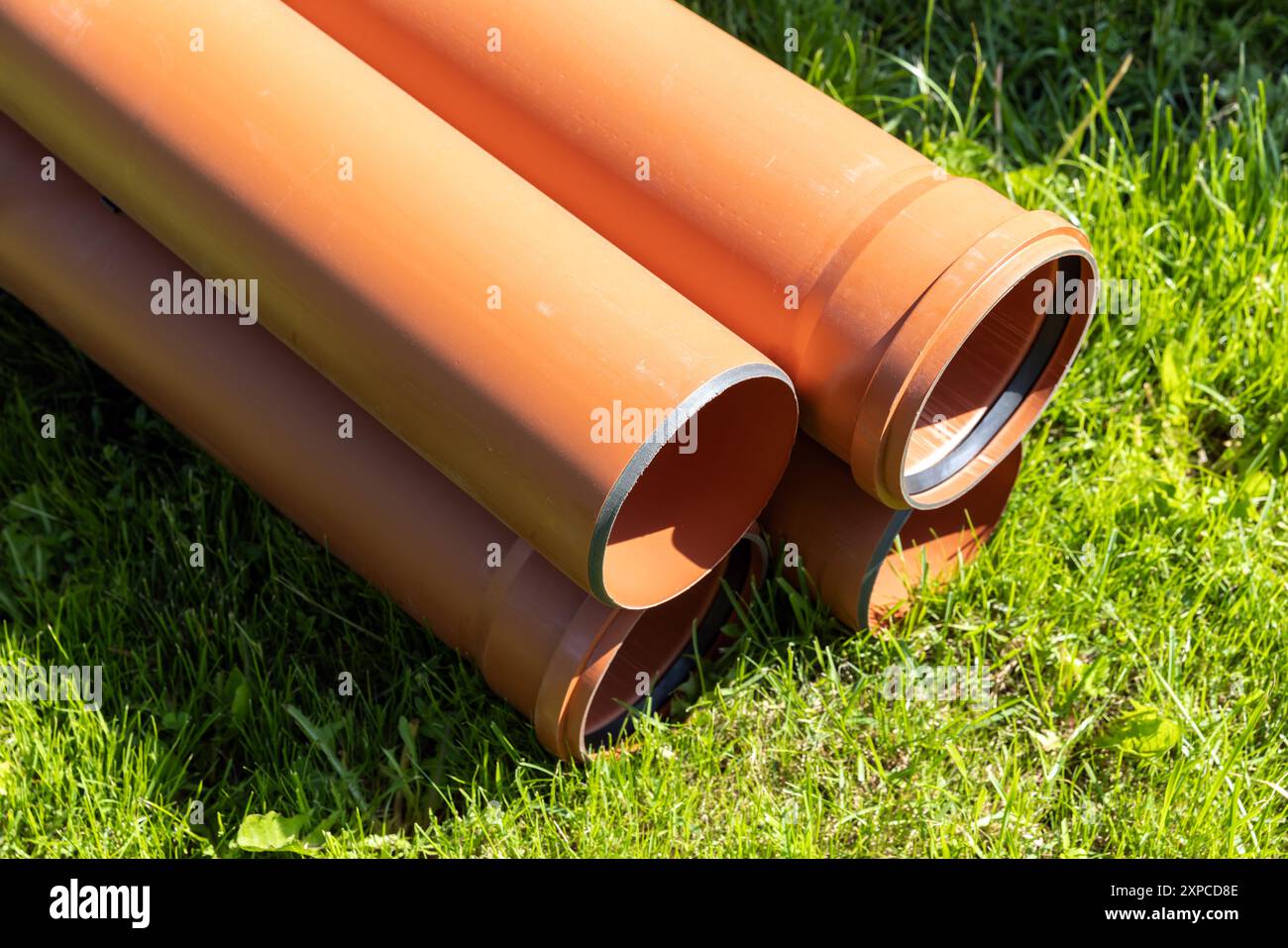 Pipes for external sewerage lay on green grass on a sunny day, elements ...
