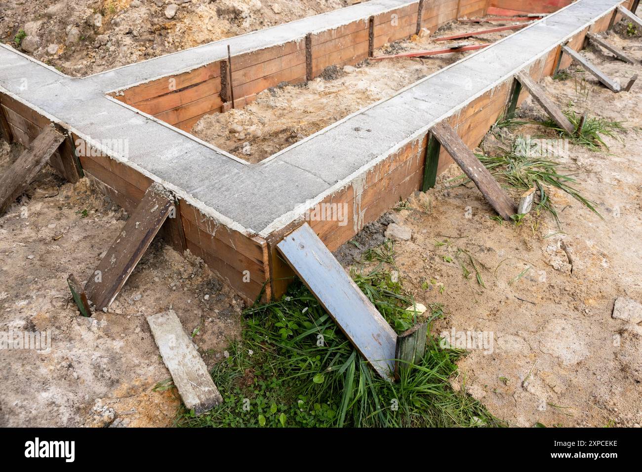 Freshly laid concrete, foundation in wooden formwork. Rural house construction is in progress ...