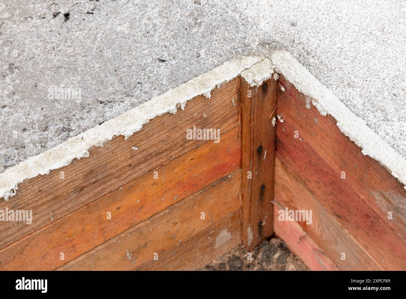 A corner of a foundation in wooden formwork with freshly laid concrete ...