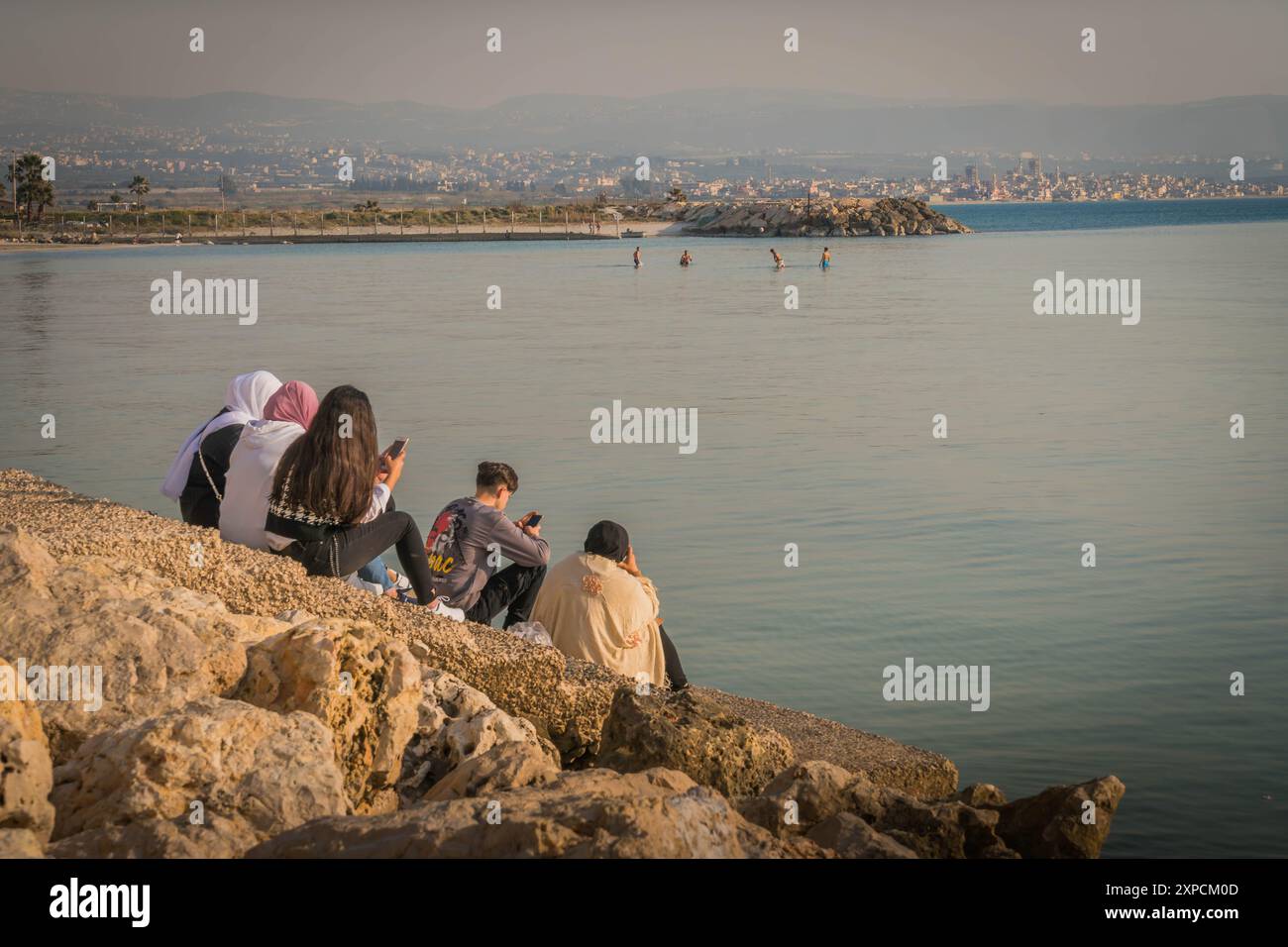 Young Arab people on the rocky shore of the Mediterranean sea in ...