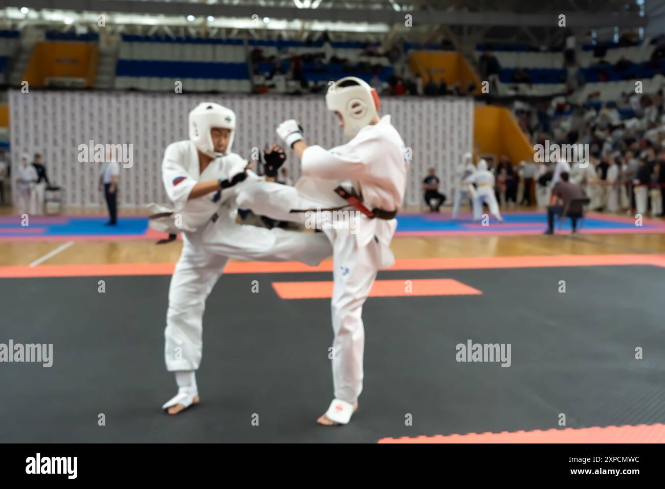 Blurred defocused image with two karate practitioners sparring on a ...