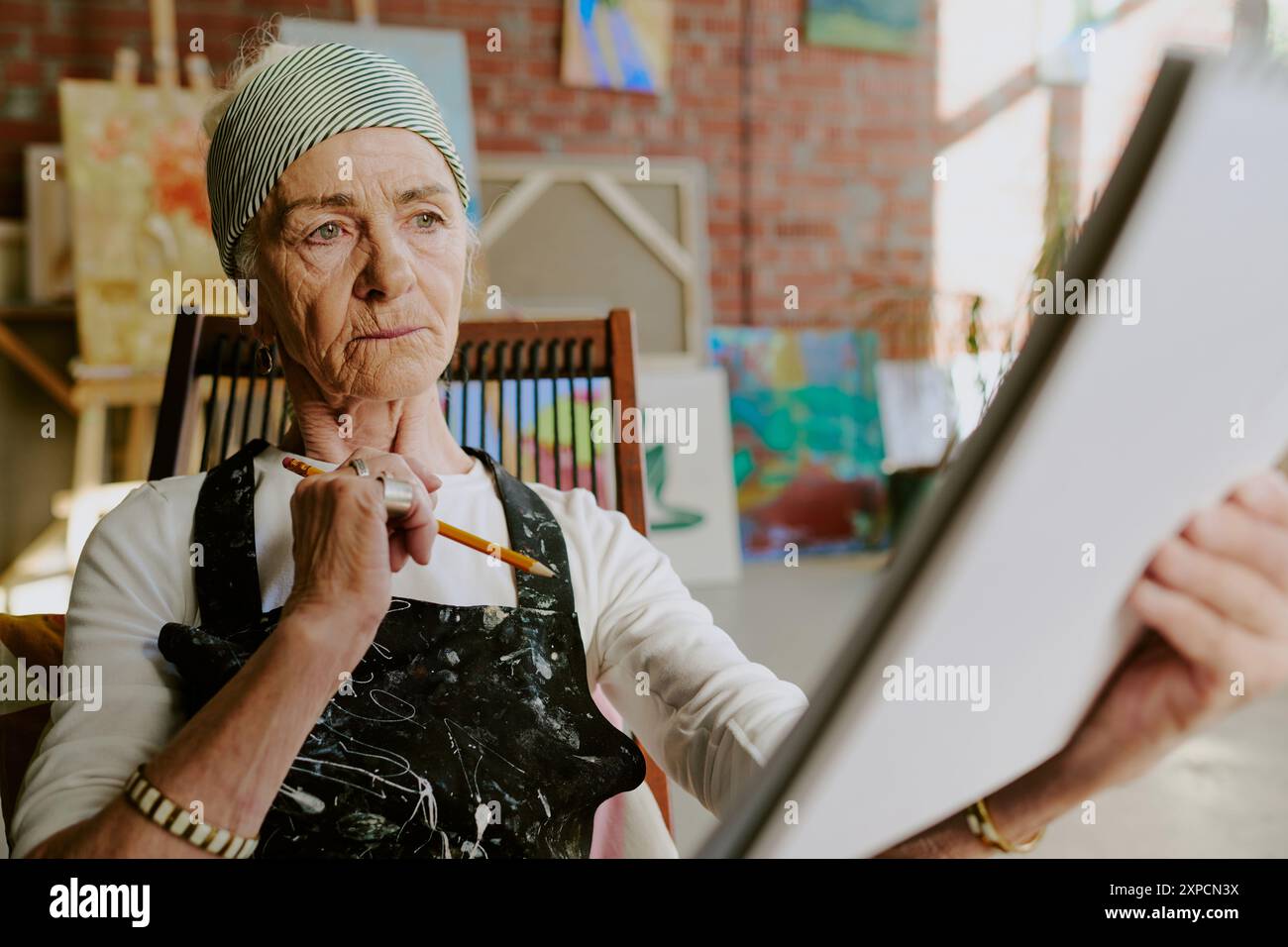 Medium closeup of focused senior Caucasian female artist looking at ...