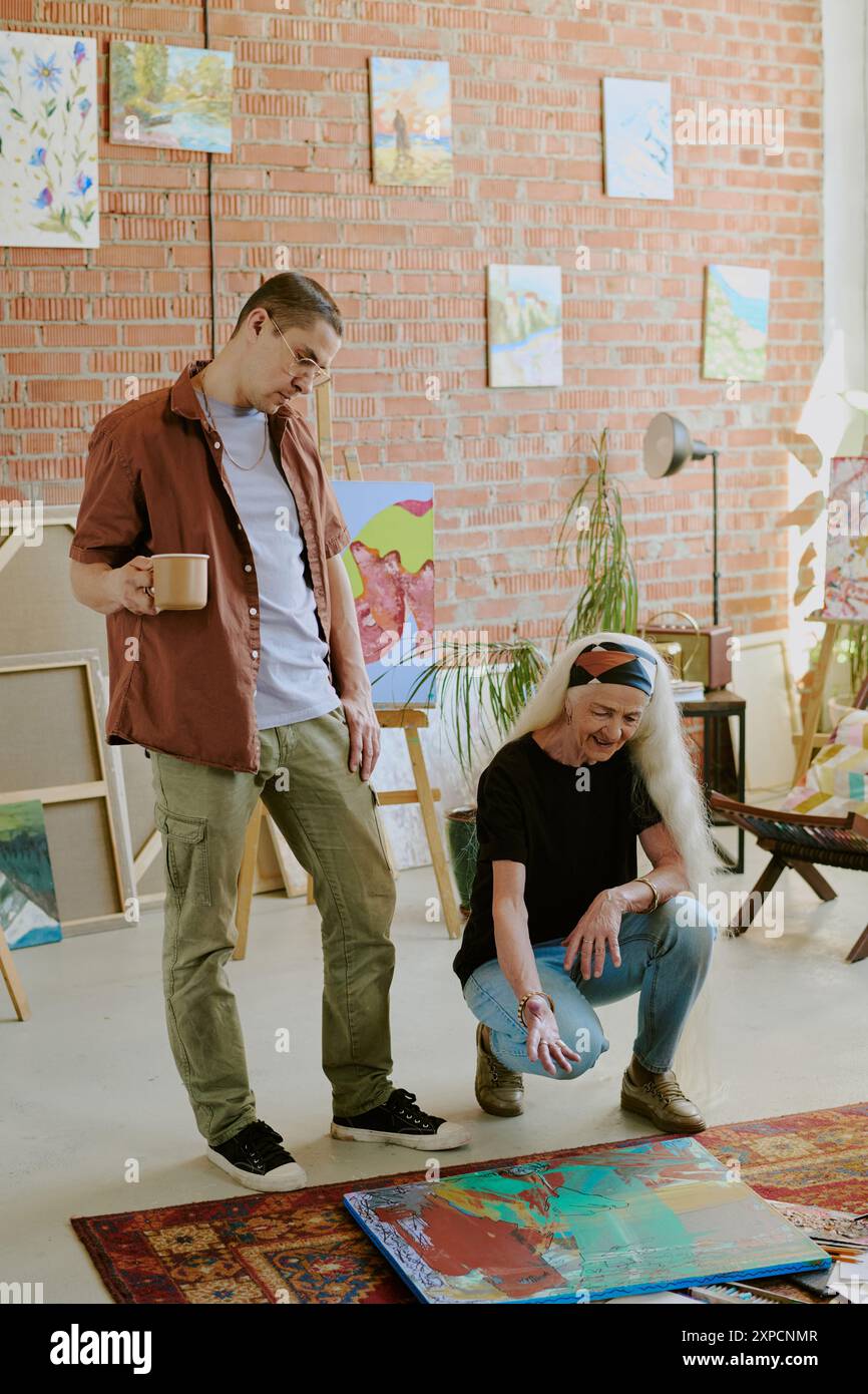 Modern senior female art teacher giving comment on abstract painting ...