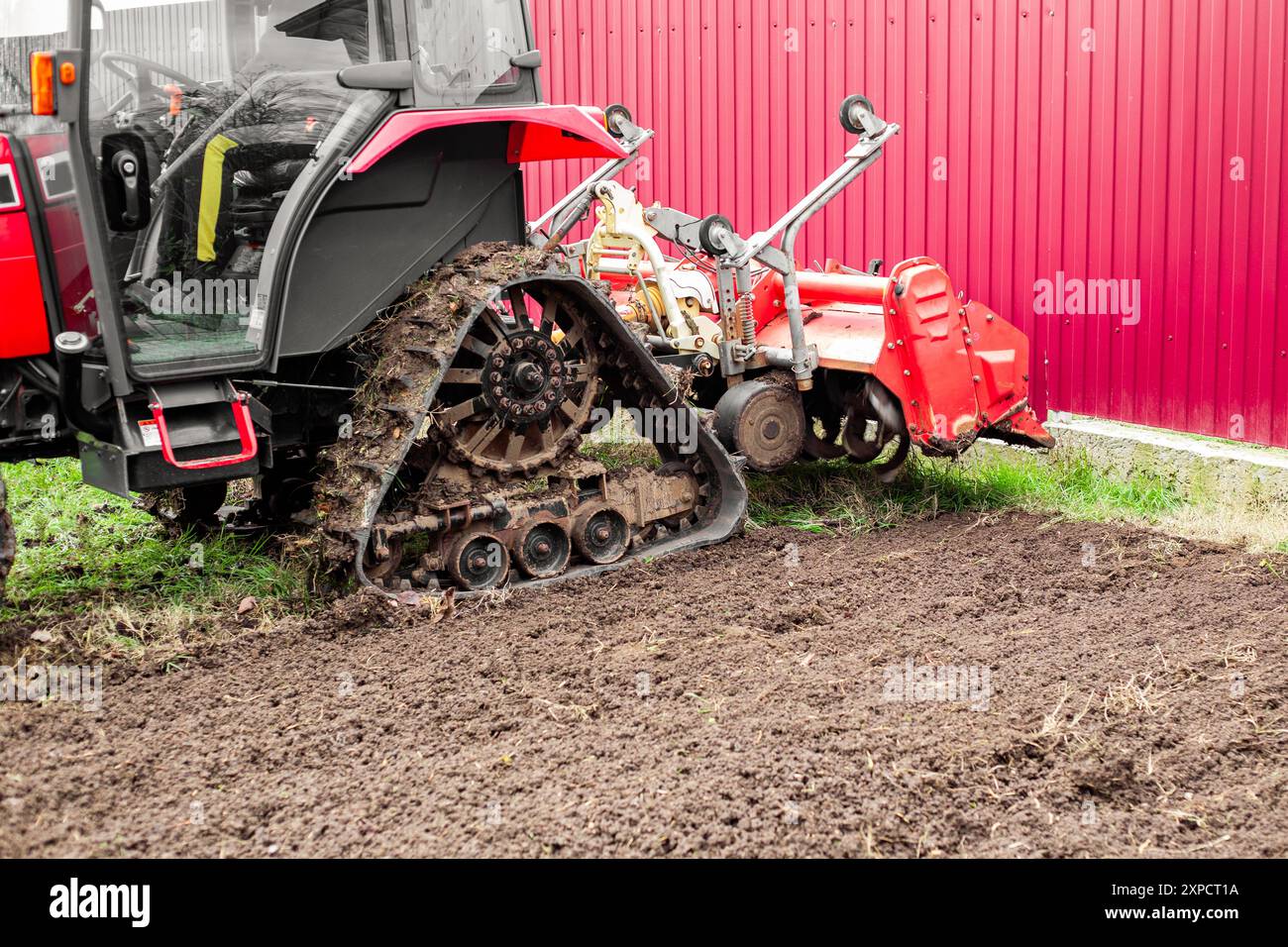A caterpillar tractor plows the land in a rural vegetable garden ...