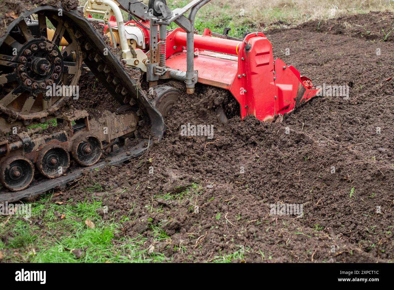 A caterpillar tractor plows the land in the garden. Earthworks on ...