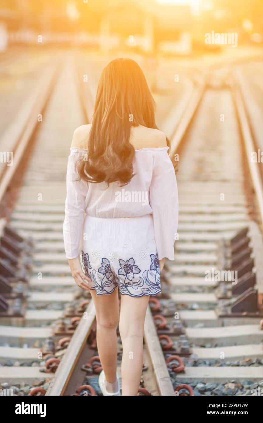Blurred image, a young woman walks alone down a railroad and towards ...