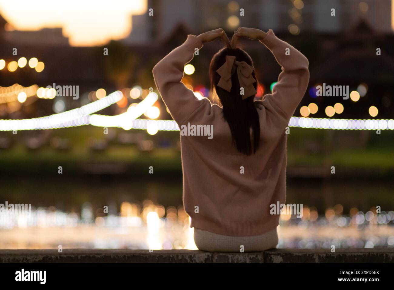A silhouette of a young woman raising her hands above her head to ...