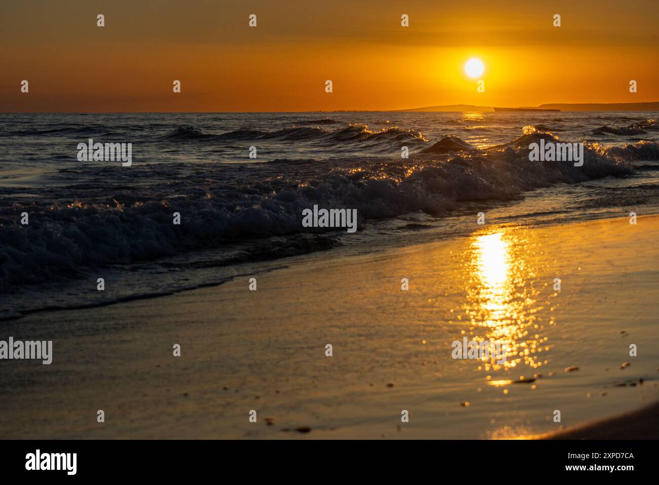 Puesta de sol en la playa de Son Bou, un horizonte dorado con el sol ...