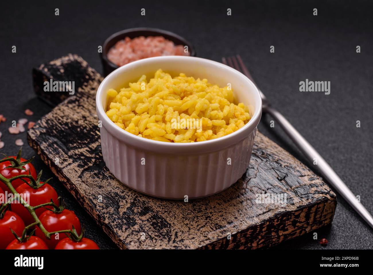 Delicious boiled yellow rice with turmeric, salt and spices on a dark ...