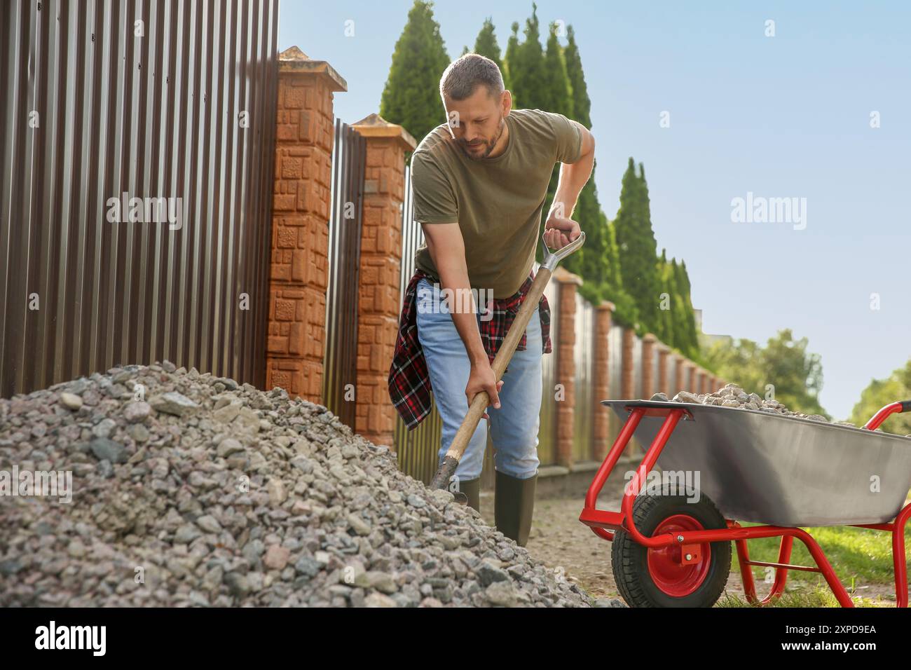 Man picking stones up with shovel and wheelbarrow outdoors Stock Photo ...