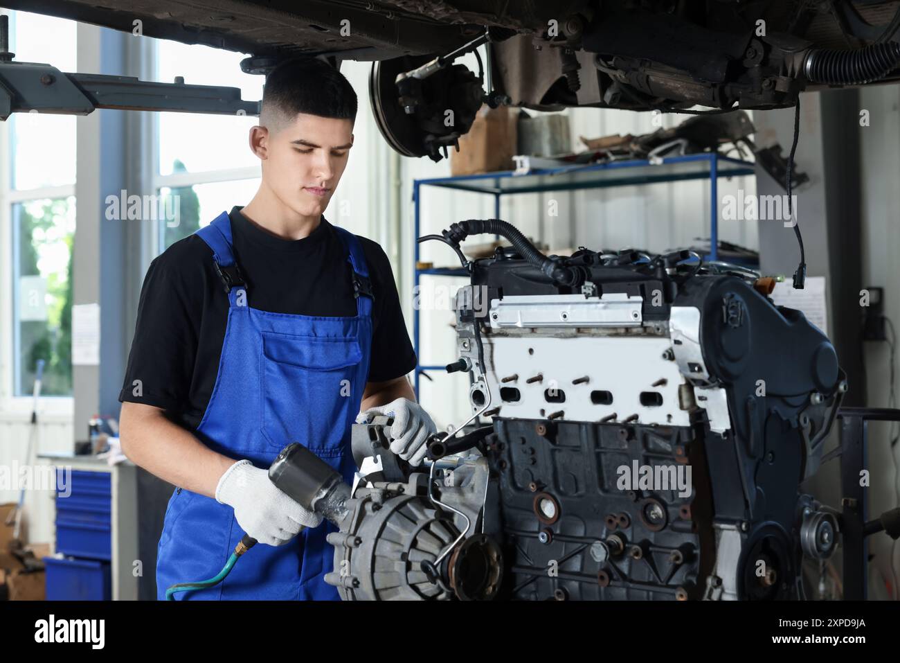 Young auto mechanic fixing motor at automobile repair shop. Car ...