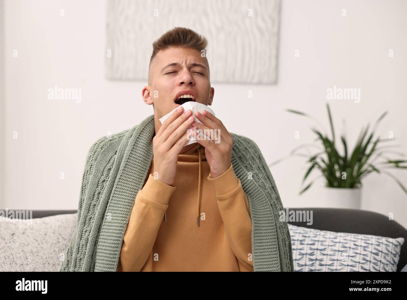 Cold symptom. Young man with runny nose at home Stock Photo - Alamy
