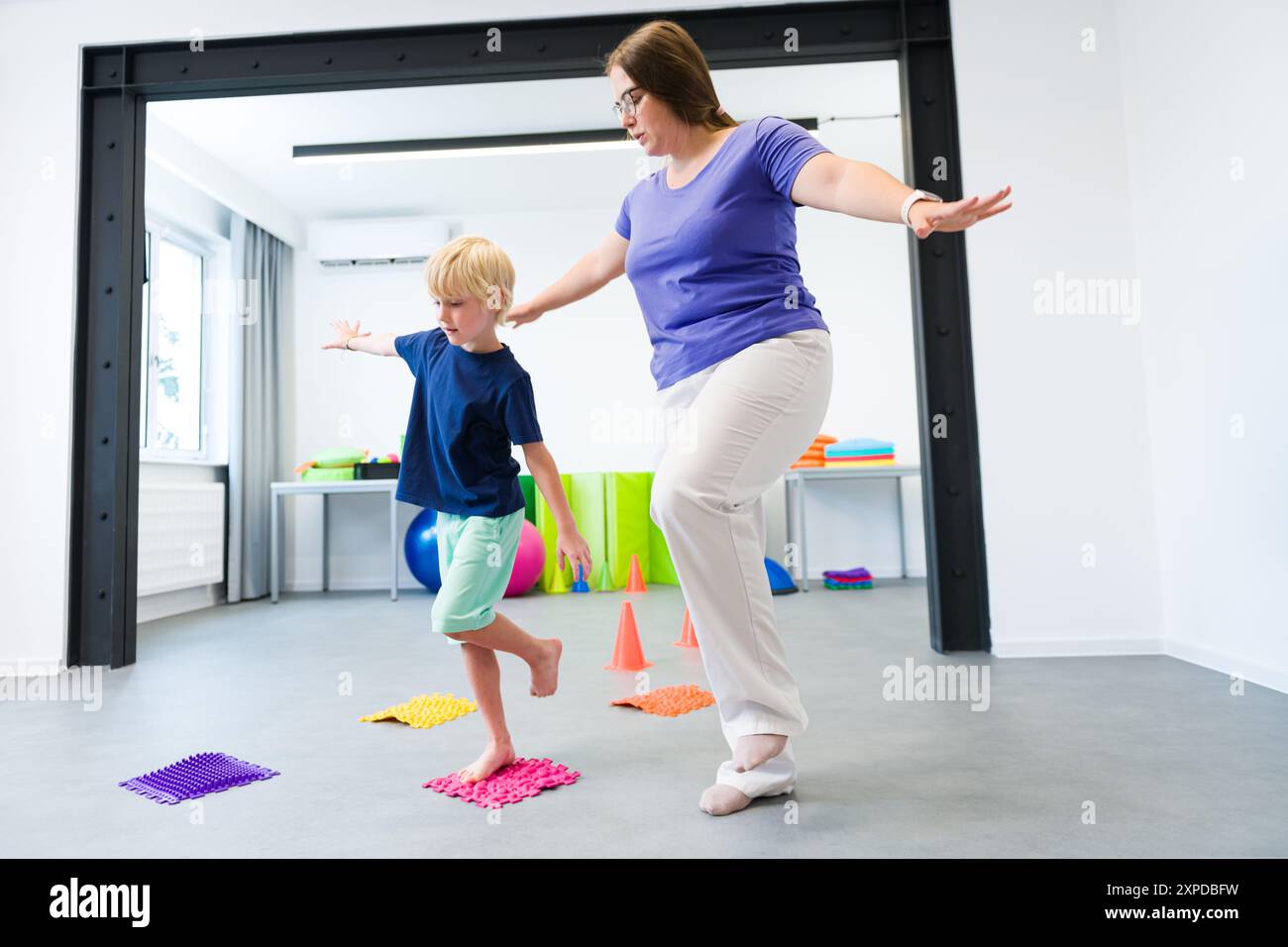 Kids physio therapy. Child and female physical therapist exercising during session. Bilateral ...