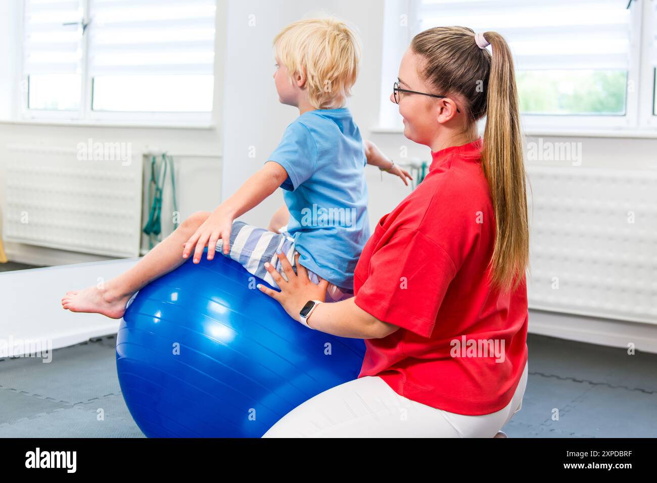 Young boy with female therapist exercising during physical therapy ...