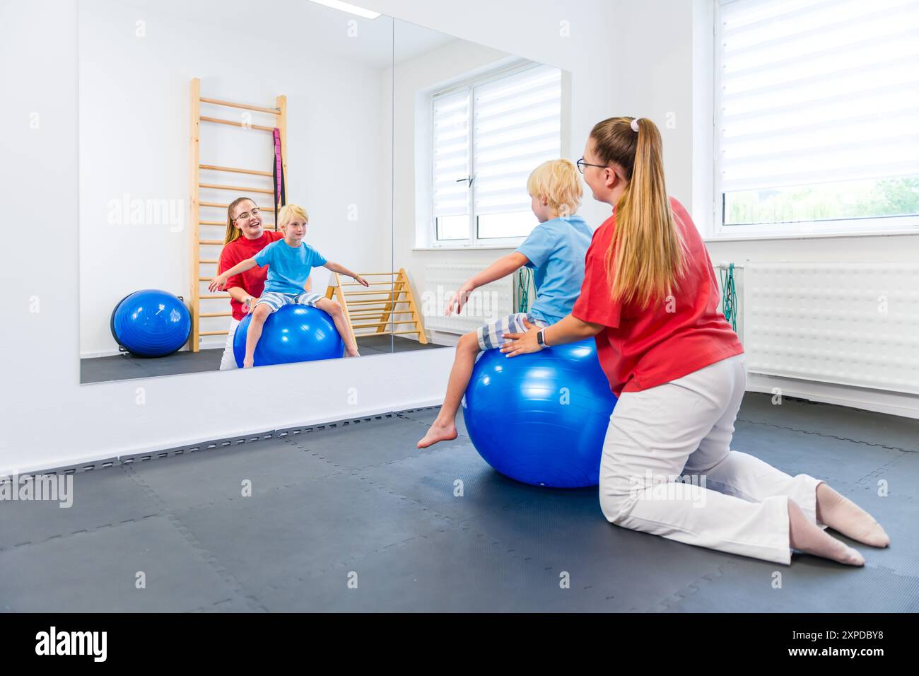 Young boy with female therapist exercising during physical therapy ...