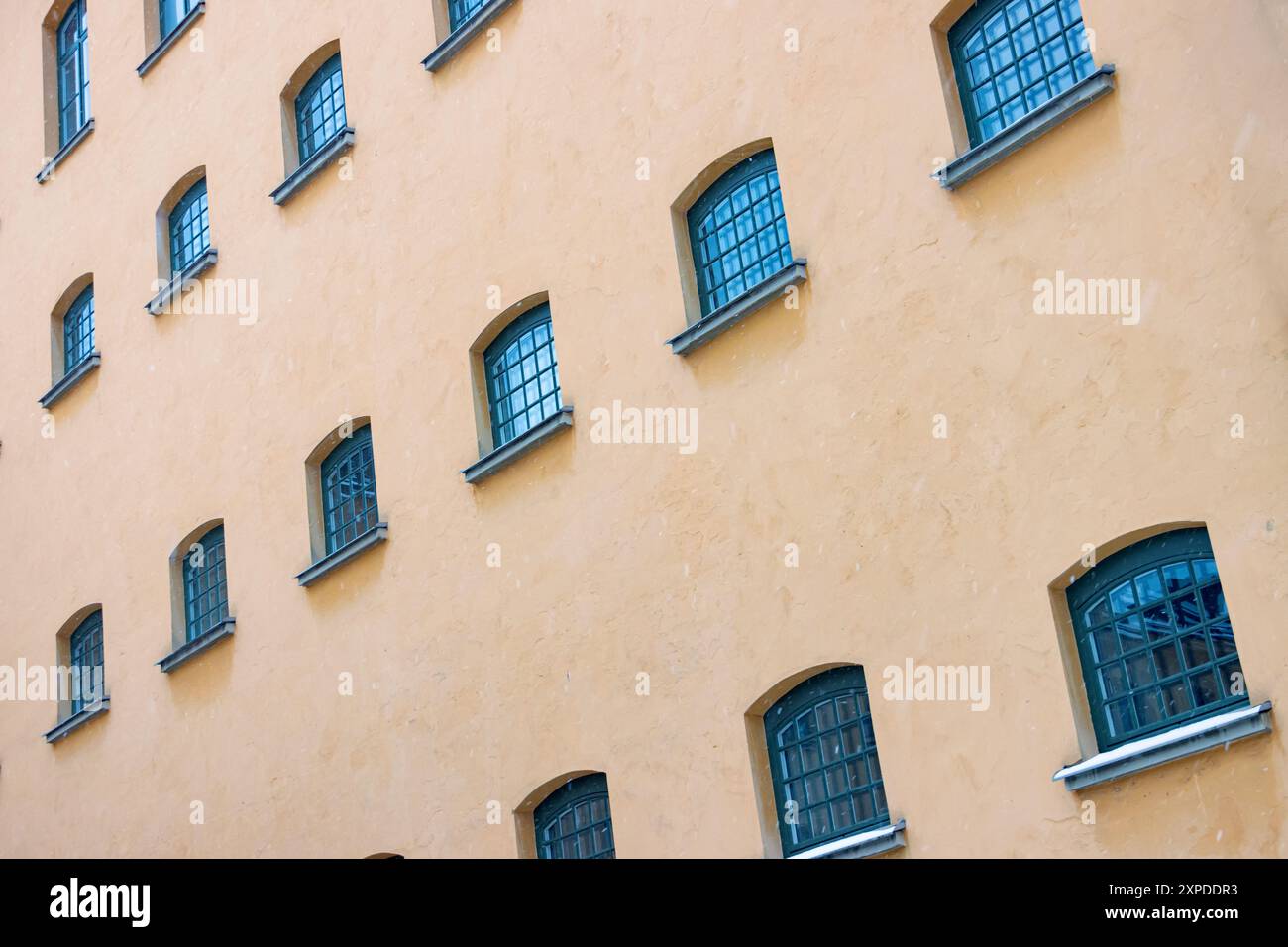 Facade of a former prison with barred windows with falling snow Stock ...