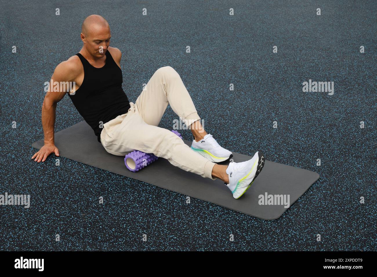 Athlete man exercising and stretching legs on foam roller on sports ...