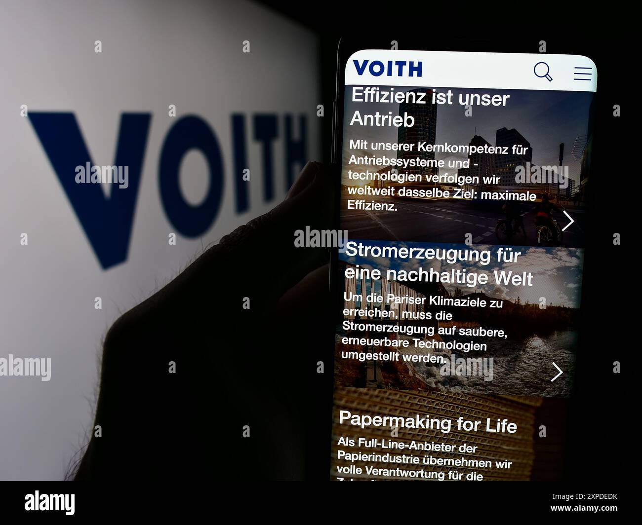 Person holding cellphone with webpage of German technology company ...