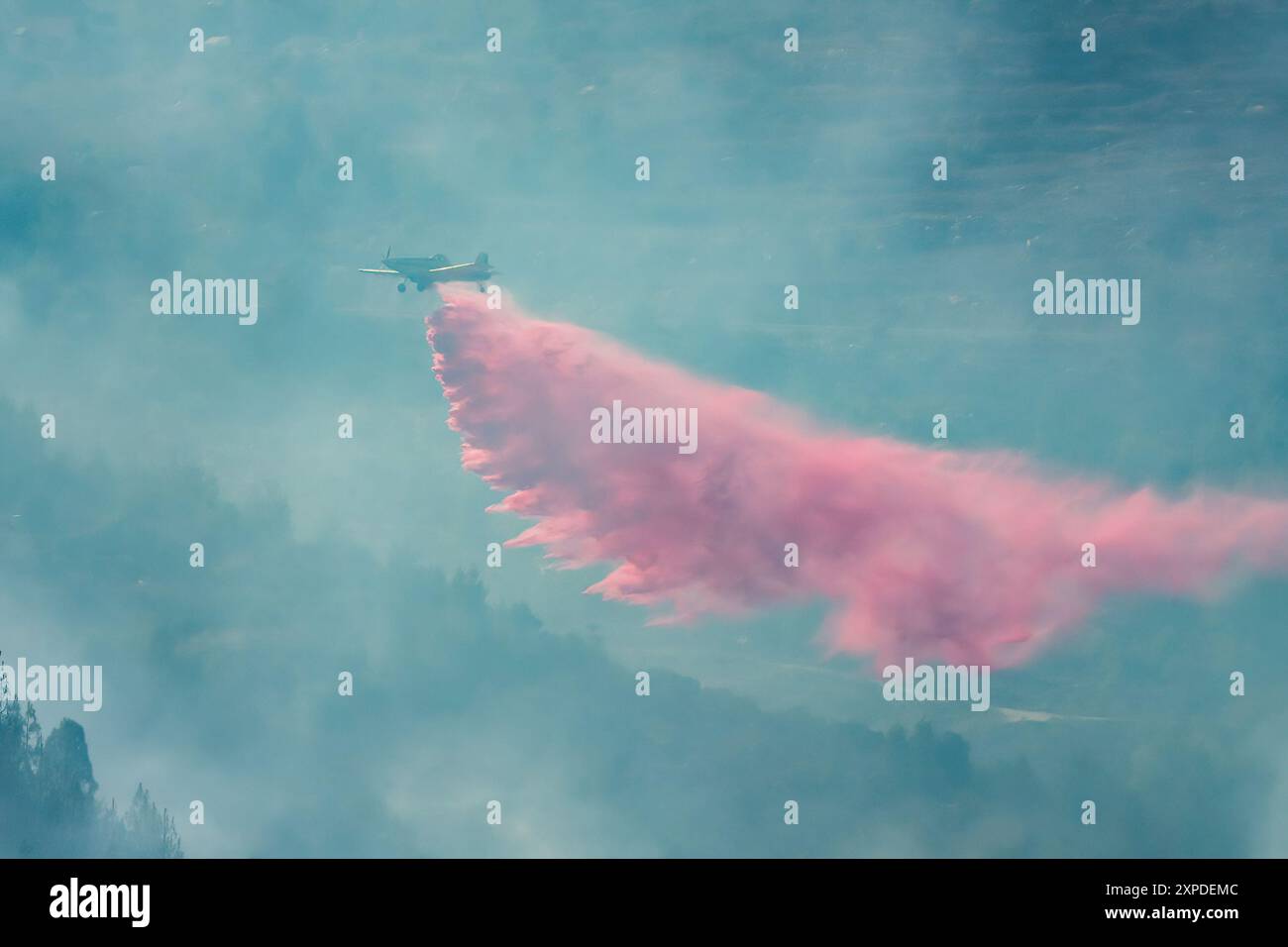 A firefighting airplane flying through smoke, dumping fire retardant ...