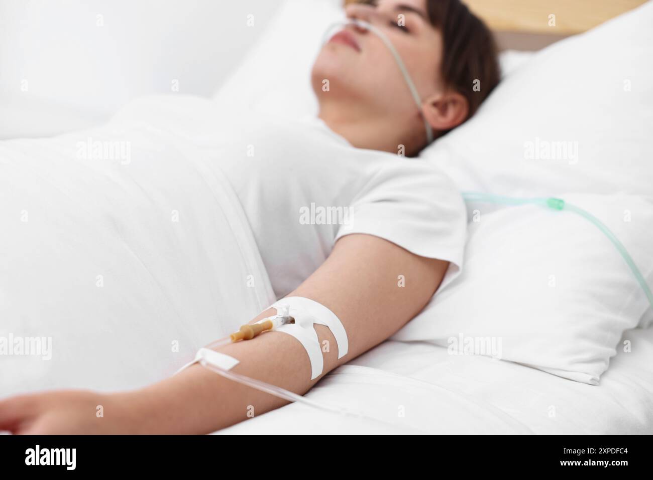 Coma patient. Young woman with intravenous drip in hospital bed ...