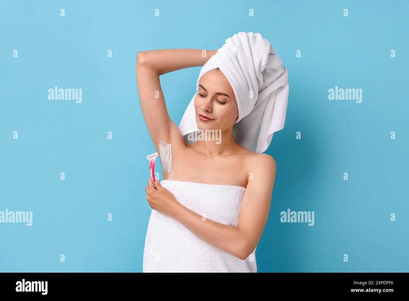 Beautiful woman shaving armpit on light blue background Stock Photo - Alamy