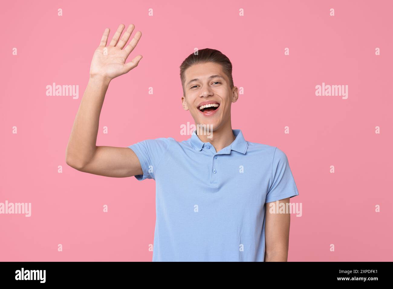 Goodbye gesture. Happy young man waving on pink background Stock Photo ...