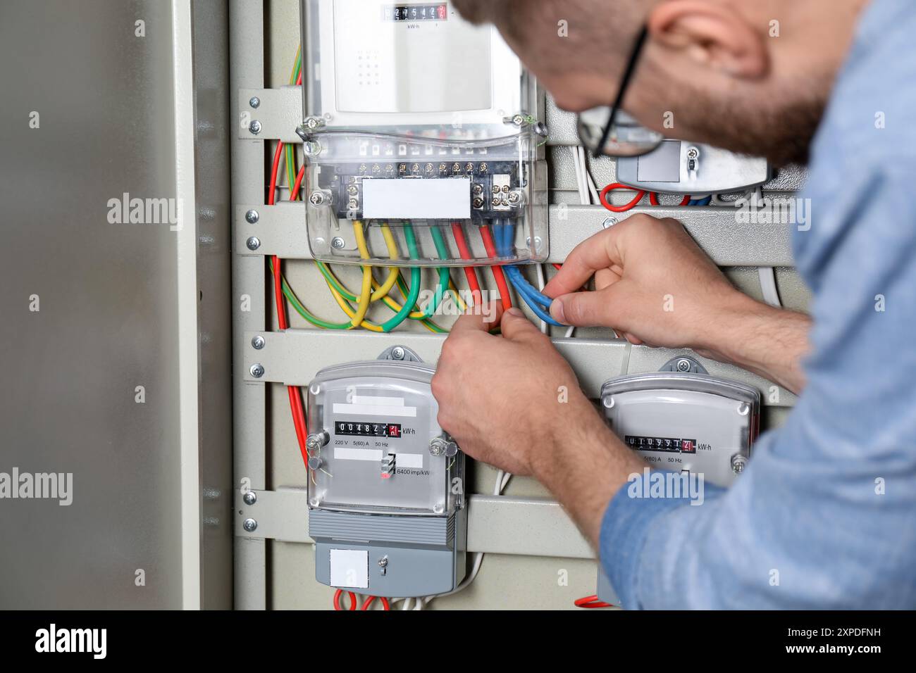 Man checking connecting cables on electricity meter indoors, closeup ...