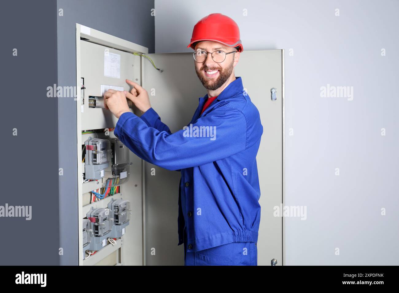 Electrician wearing uniform installing electricity meter indoors Stock ...