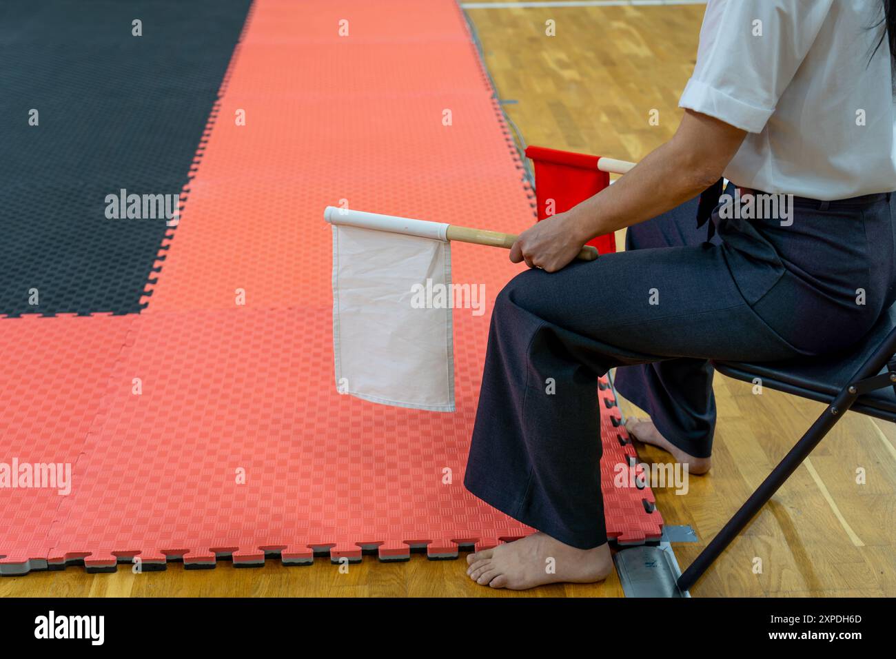The karate referee sitting beside the mat with red and white flags in ...