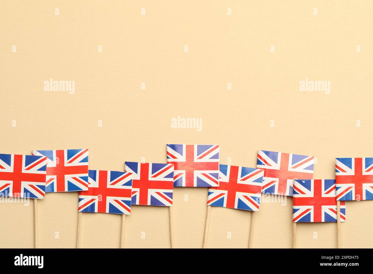 Small paper flags of United Kingdom on beige background, top view ...