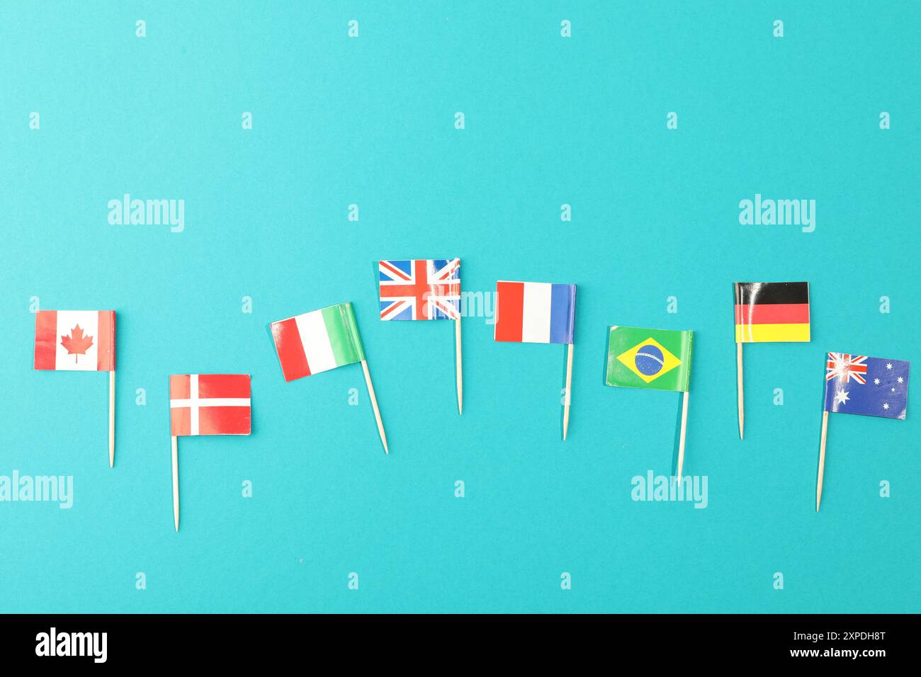 Small paper flags of different countries on light blue background, flat ...