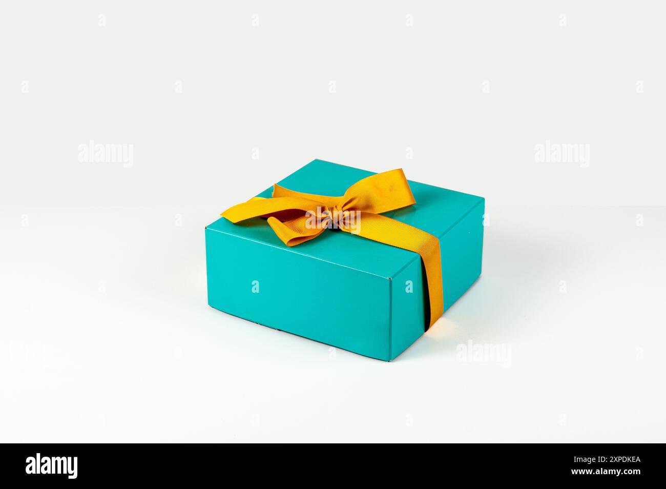 Teal colored gift box with gold ribbon on a white background - concept ...