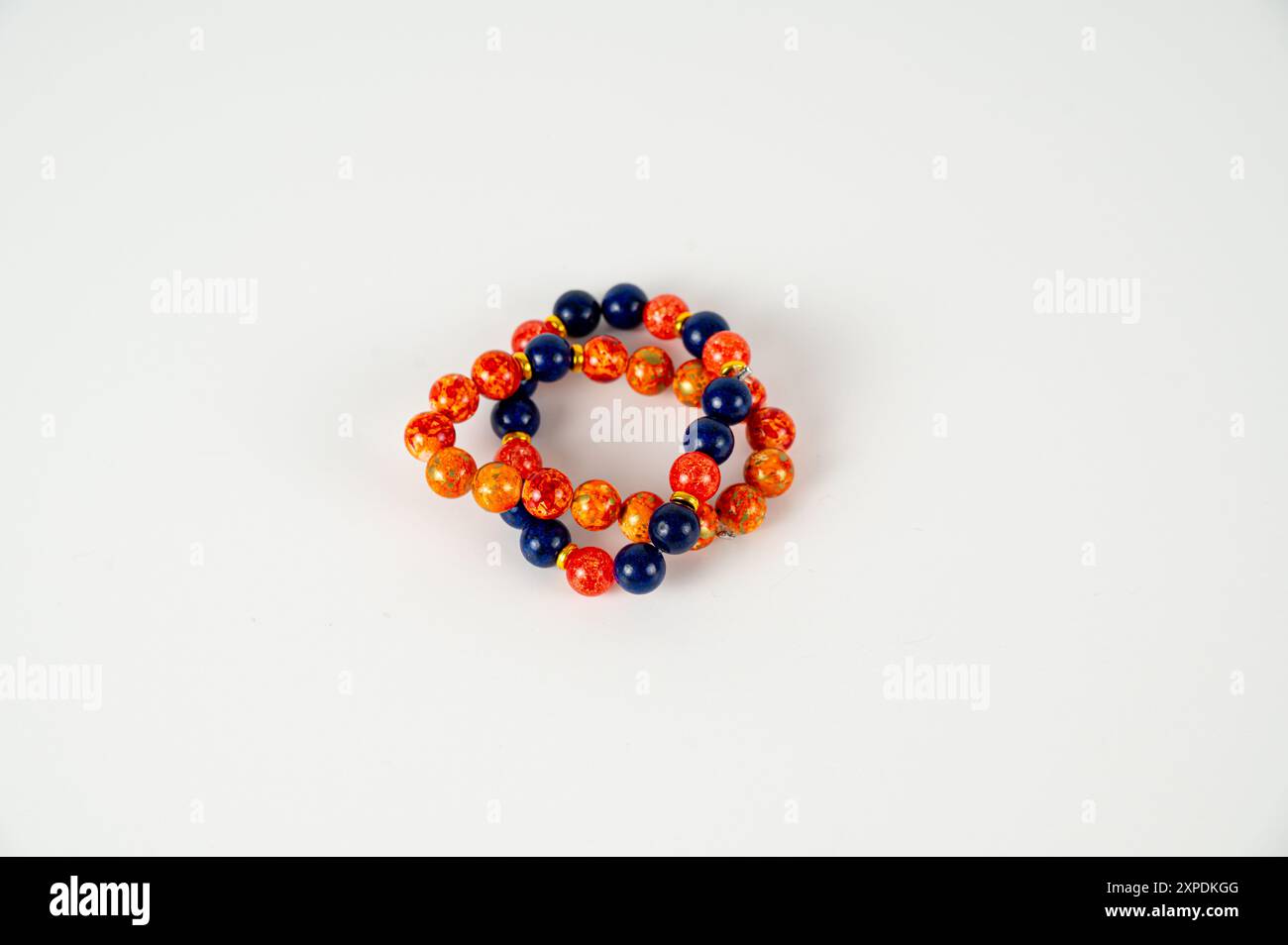 Handmade orange and black beaded bracelets intertwined on white ...