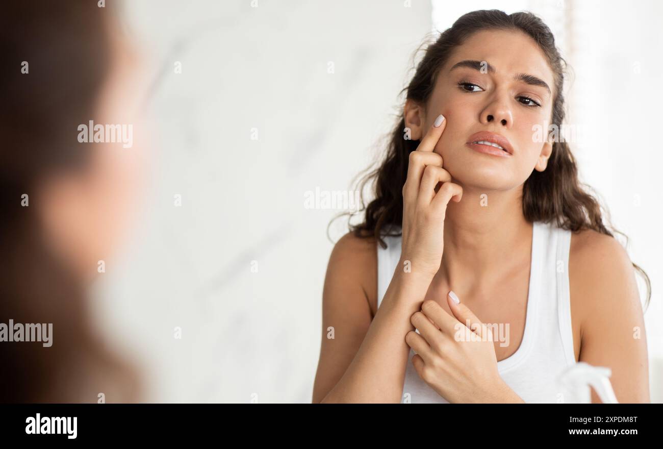 Depressed Woman Touching Pimple On Face In Modern Bathroom Stock Photo ...