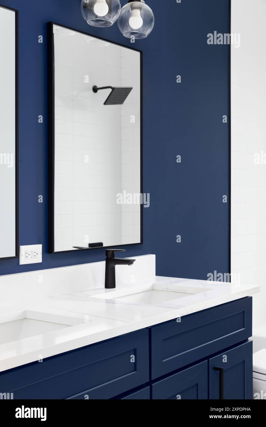 A bathroom detail with blue walls and cabinet, white marble countertop ...