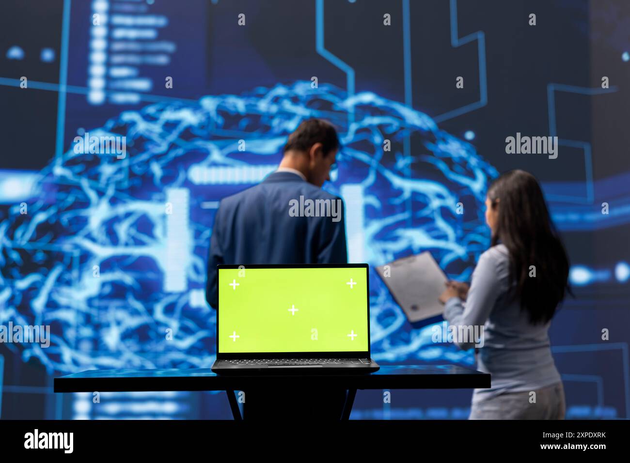Focus on green screen laptop used by teamworking AI technicians in blurry background using for ...