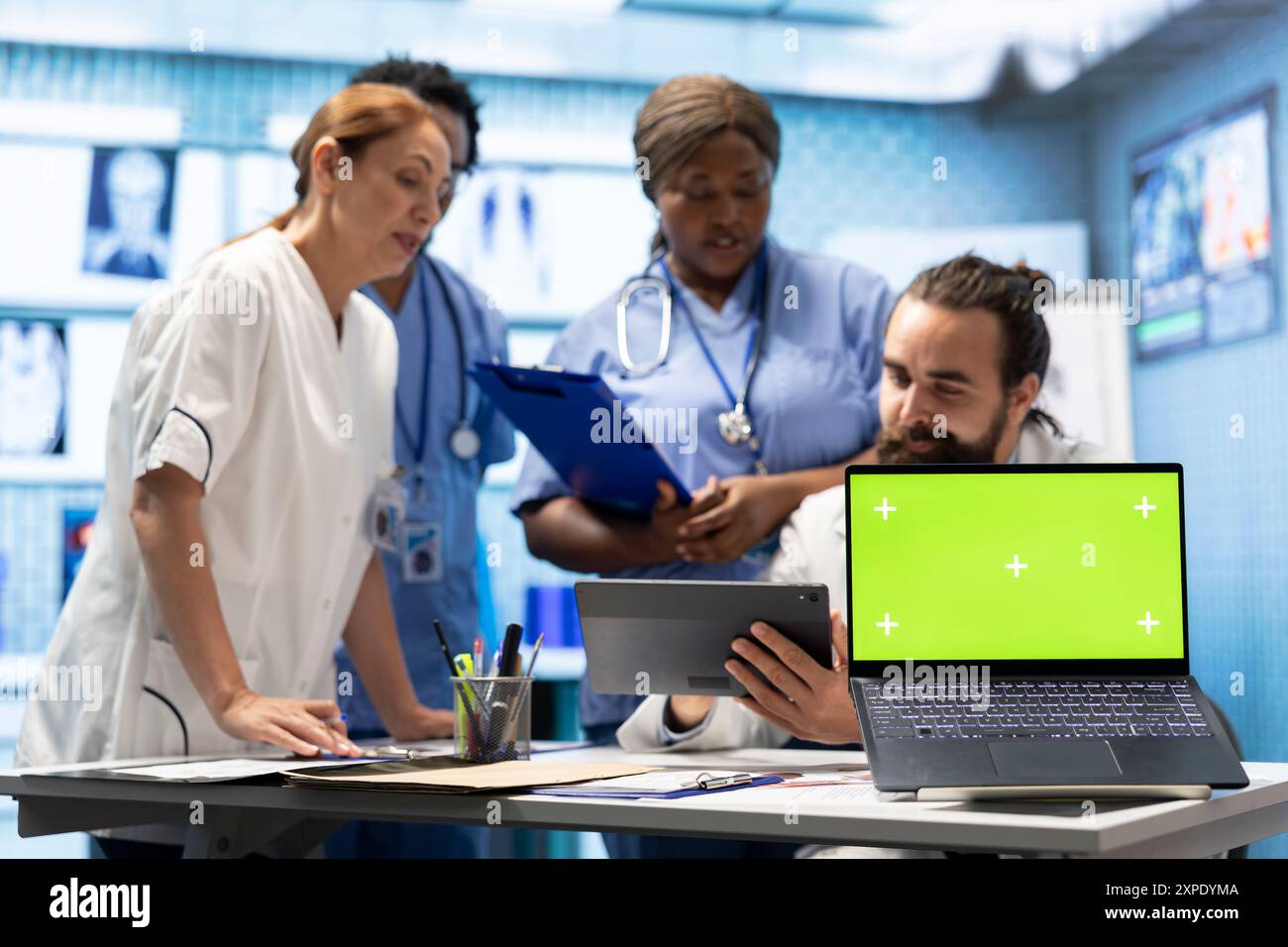 Doctors and nurses review radiography scans with a green screen on desk ...