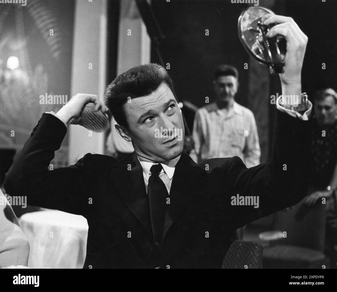 LAURENCE HARVEY combing his hair before filming a scene for ROOM AT THE ...