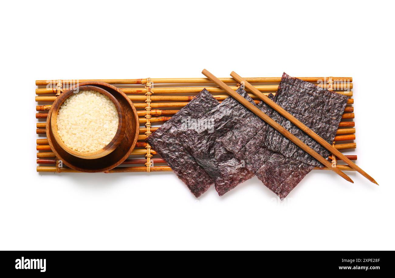 Bamboo mat with natural nori sheets and bowl of rice isolated on white ...