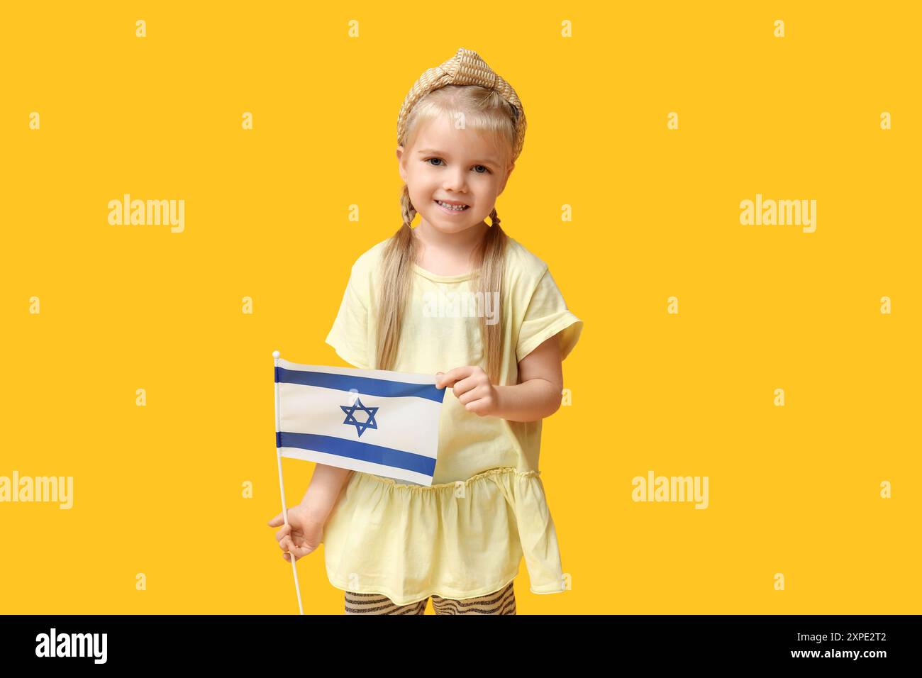 Cute happy little girl with Israel flag on yellow background. Hanukkah ...