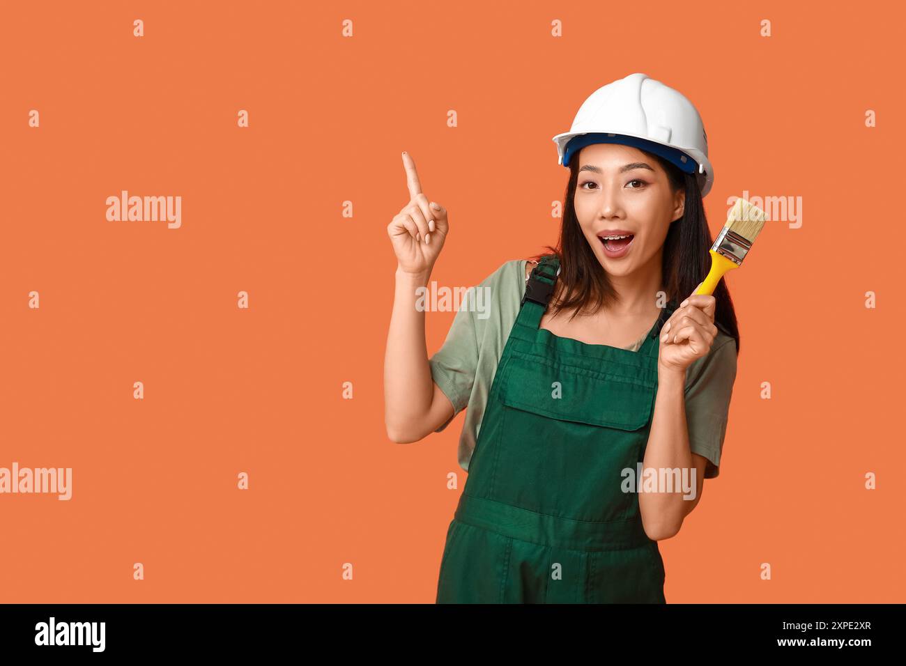 Female Asian shocked painter with paint brush pointing at something on ...