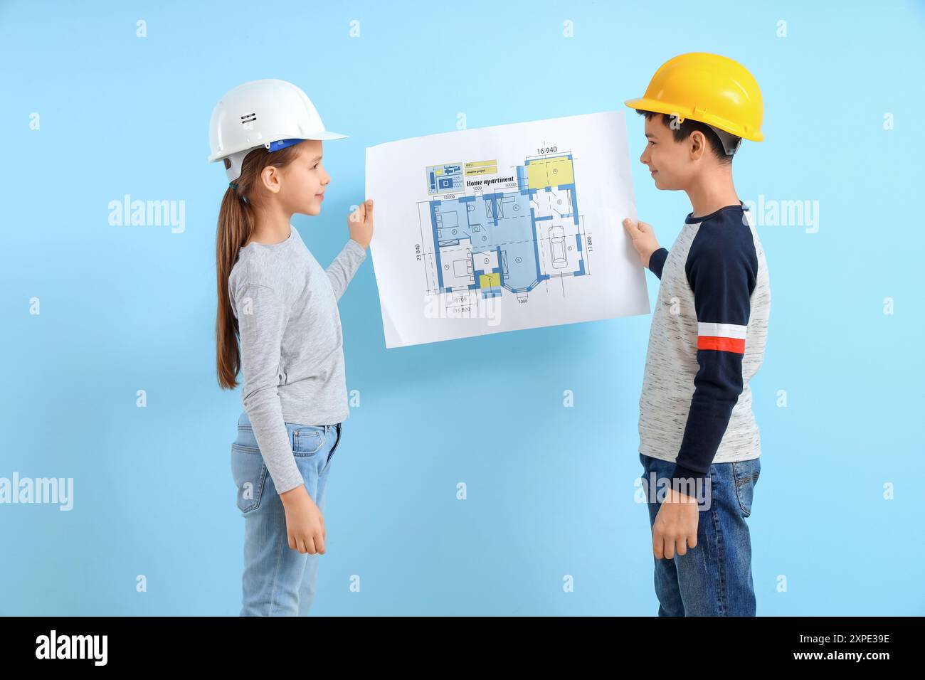 Little architects with house plan on blue background Stock Photo - Alamy