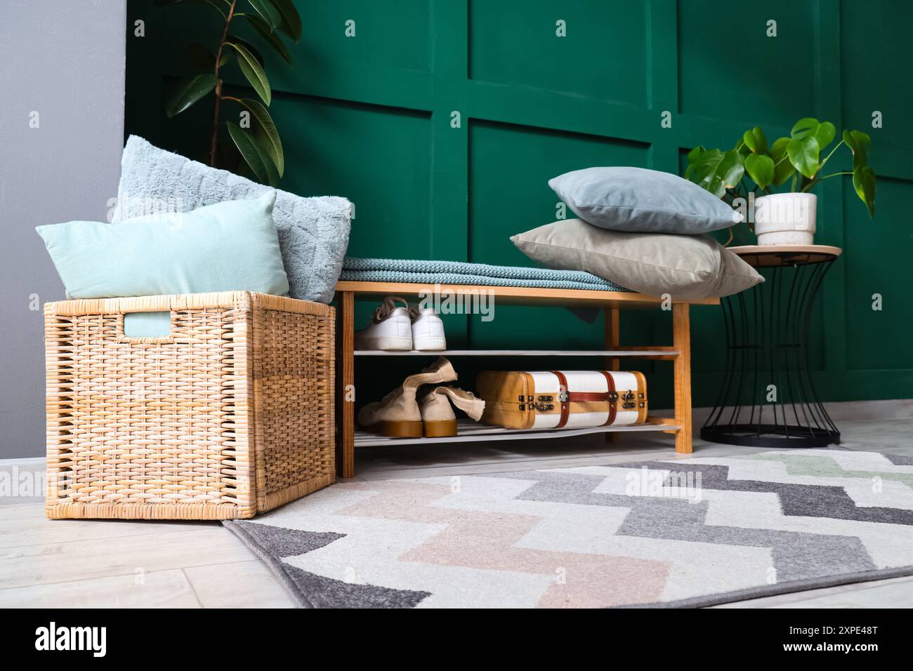 Cozy bench, shoes, coffee table and houseplant near green wall in ...